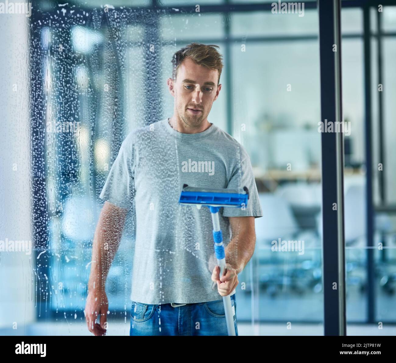 He takes pride in his cleaning. a young man cleaning the windows in the ...