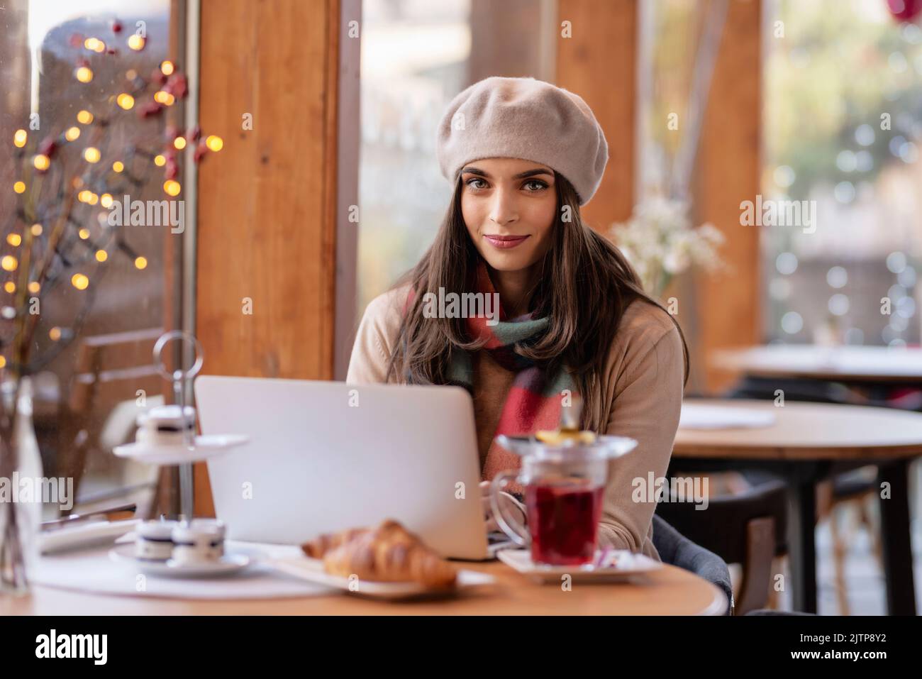 Shot of smiling beautiful woman sitting inside a coffee shop and using ...