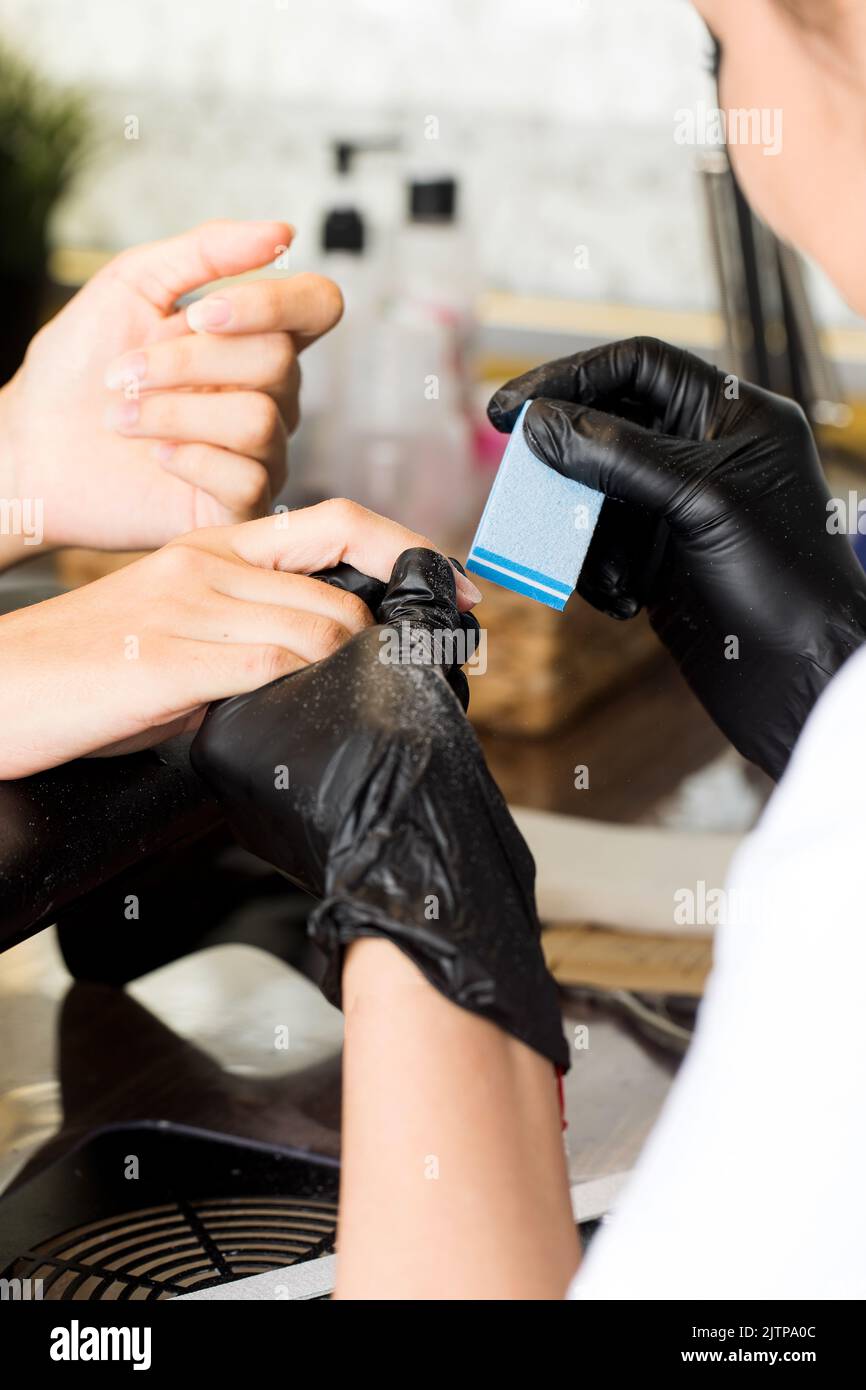 Manicurist work process. The master processes the client's nails with ...