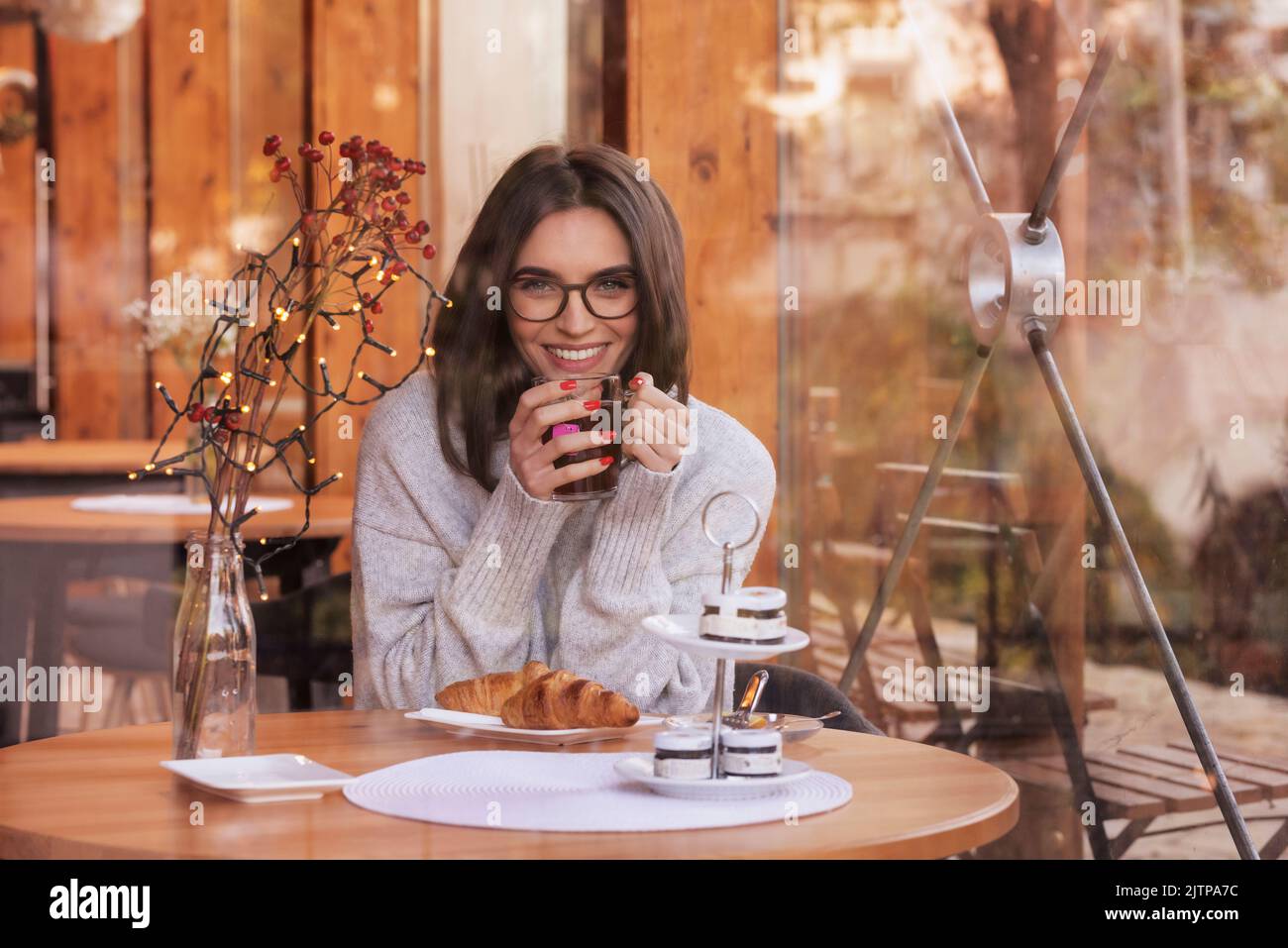 Shot of cheerful beautiful woman sitting inside a coffee shop and ...