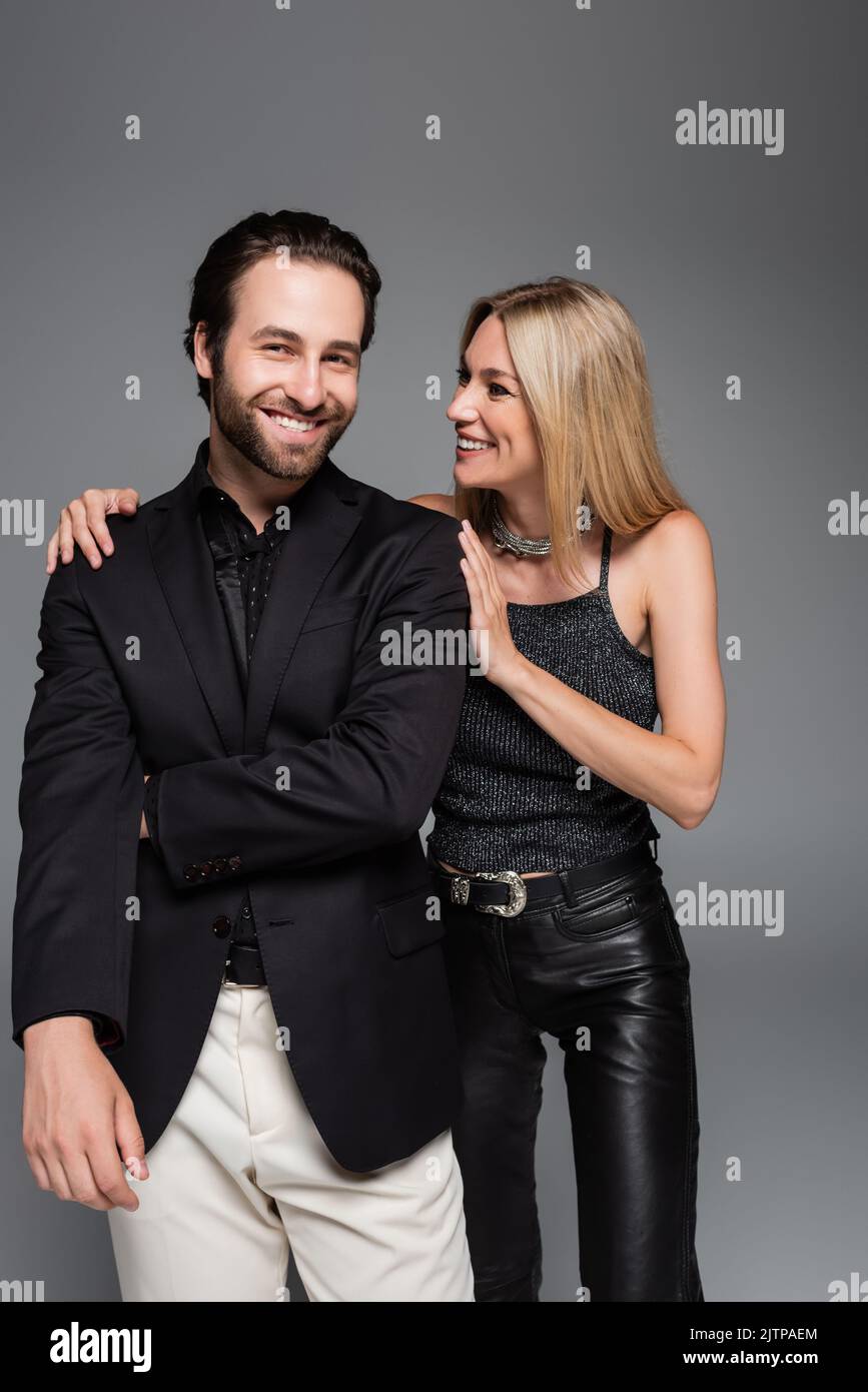 Stylish woman in leather pants hugging smiling boyfriend isolated on ...