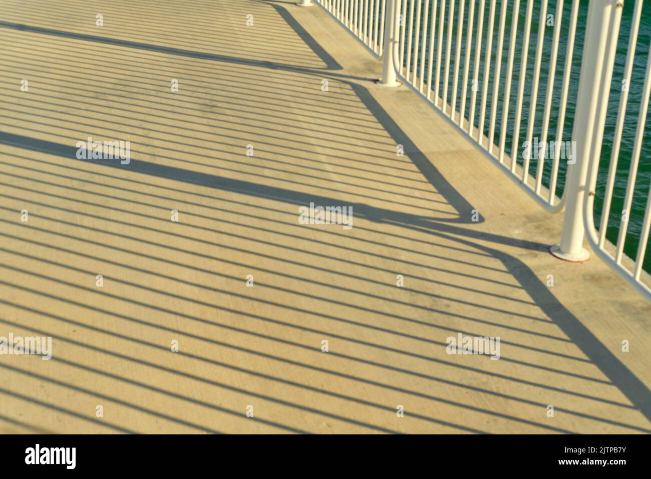 Long evening shadows from the railing on the pier Stock Photo - Alamy