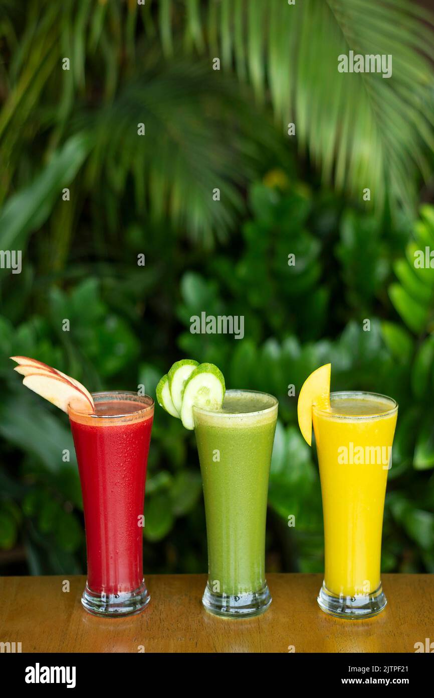 mixed organic fresh fruit juice glasses in cafe with.garden background ...