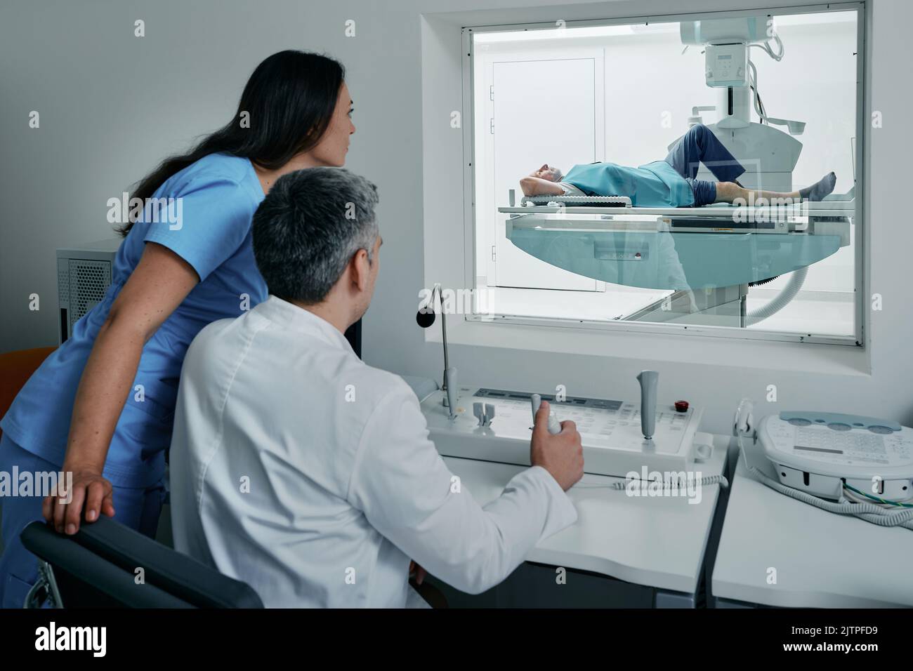 Radiologist with nurse control X-ray process from their office behind ...
