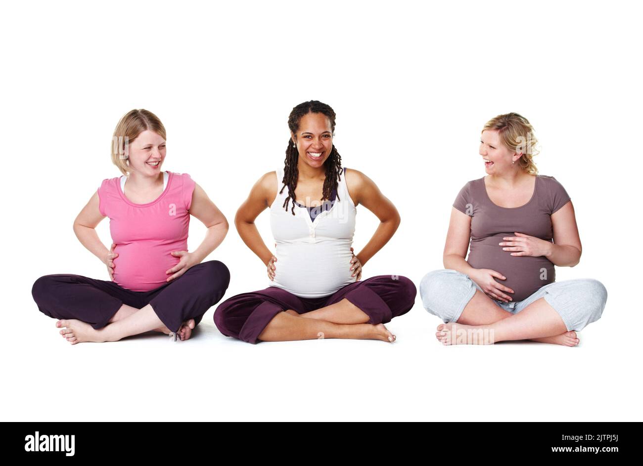Pregnant friends sitting against a studio white background, enjoying ...