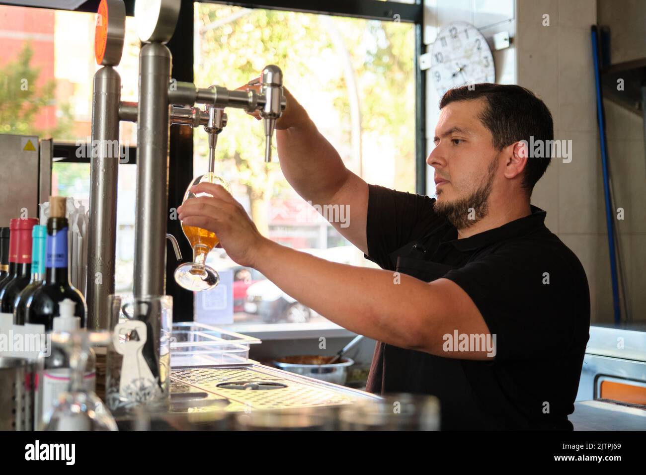 Latin bartender pouring beer from beer tap in a bar Stock Photo - Alamy