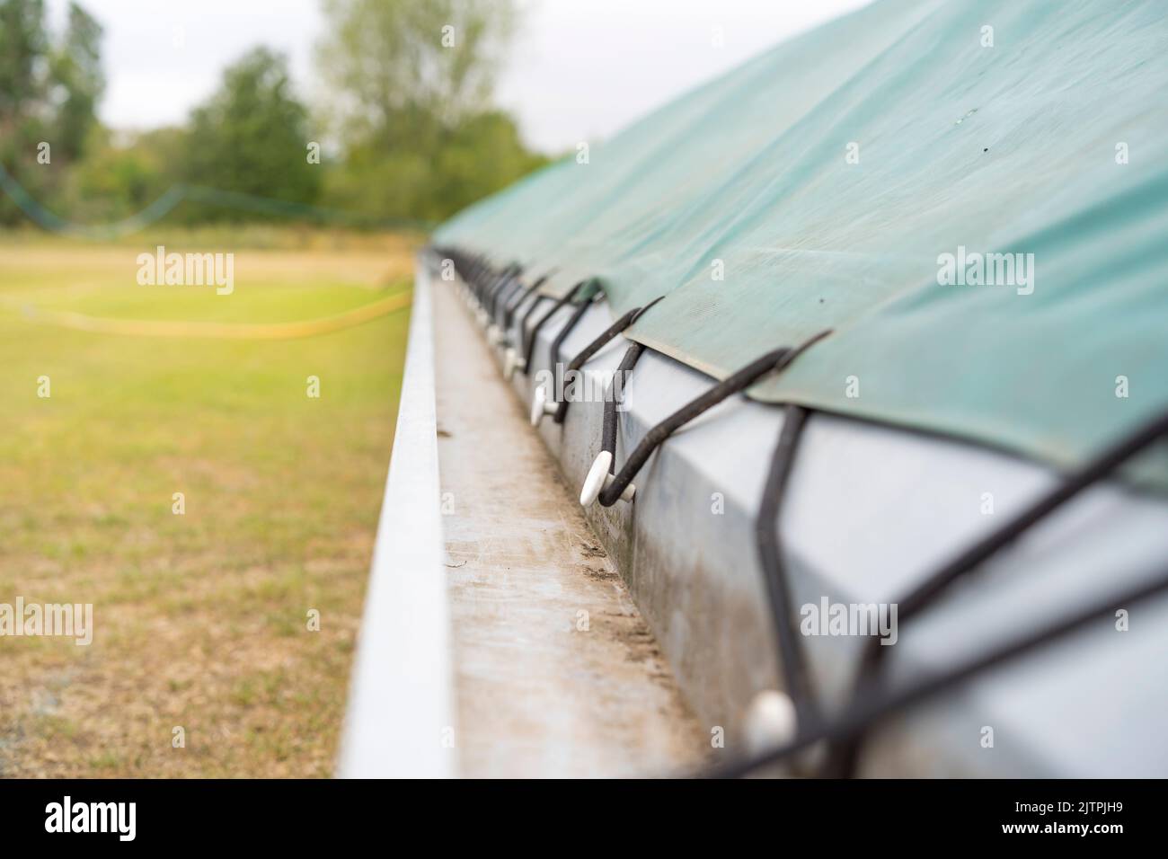 Close-up end view of a cricket pitch cover showing the drainage channel ...