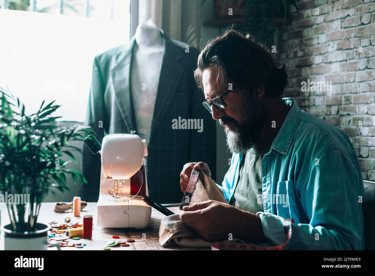 Man at home using sewing machine to tailor and modify garments. Blazer ...