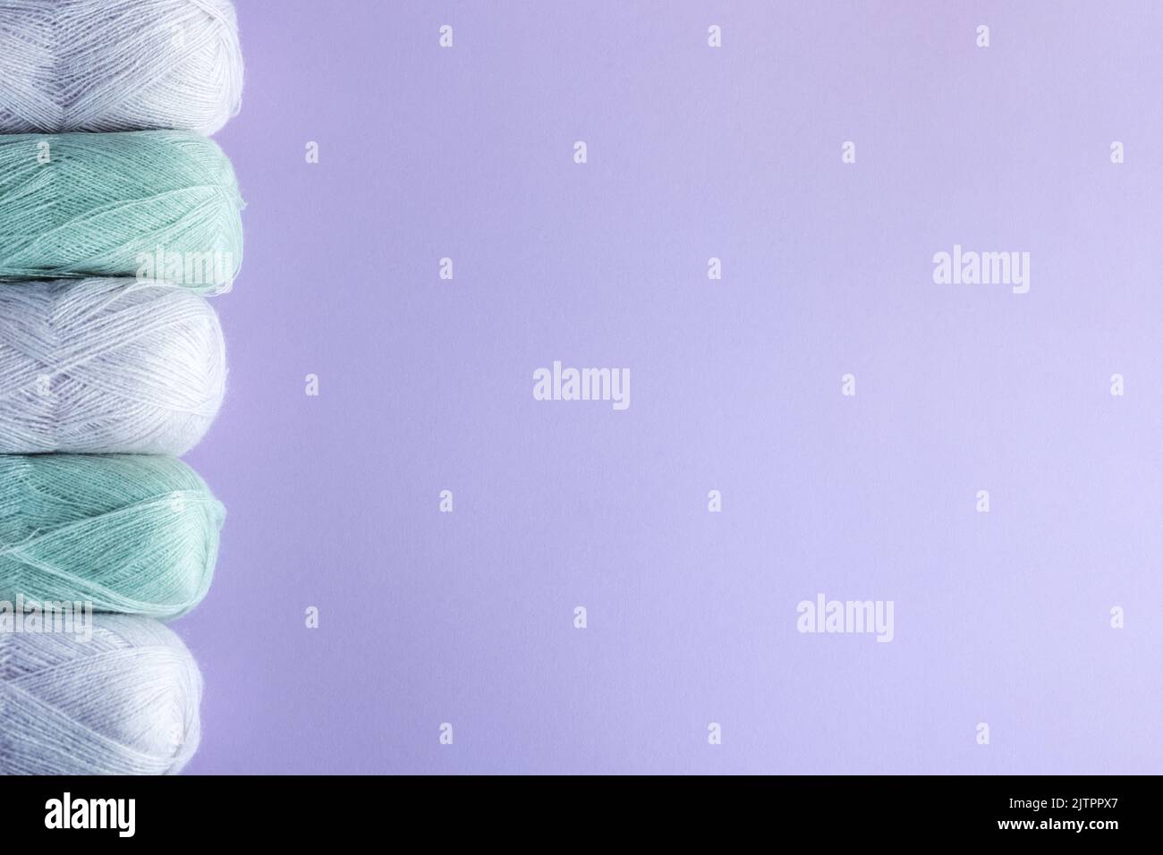 Green and pink yarn threads on a lilac background for knitting. Flat ...