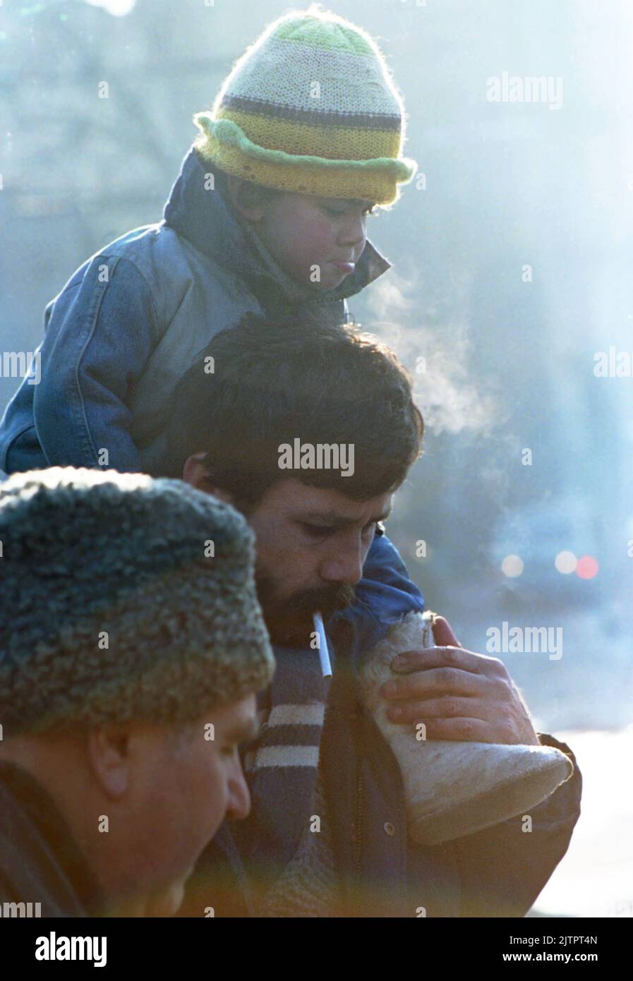 Father smoking a cigarette carrying a young child on his shoulders ...