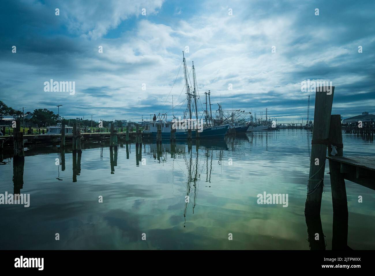 The view of docked boats under the cloudy sky reflecting on the water ...