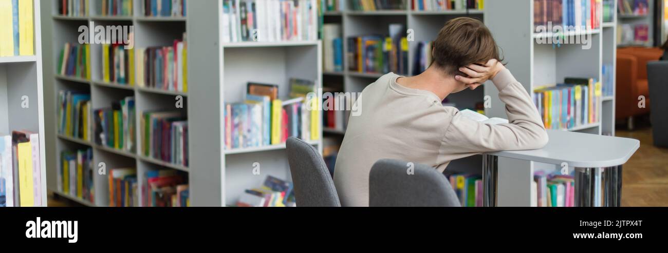 back view of teenage student sitting in library reading room, banner ...