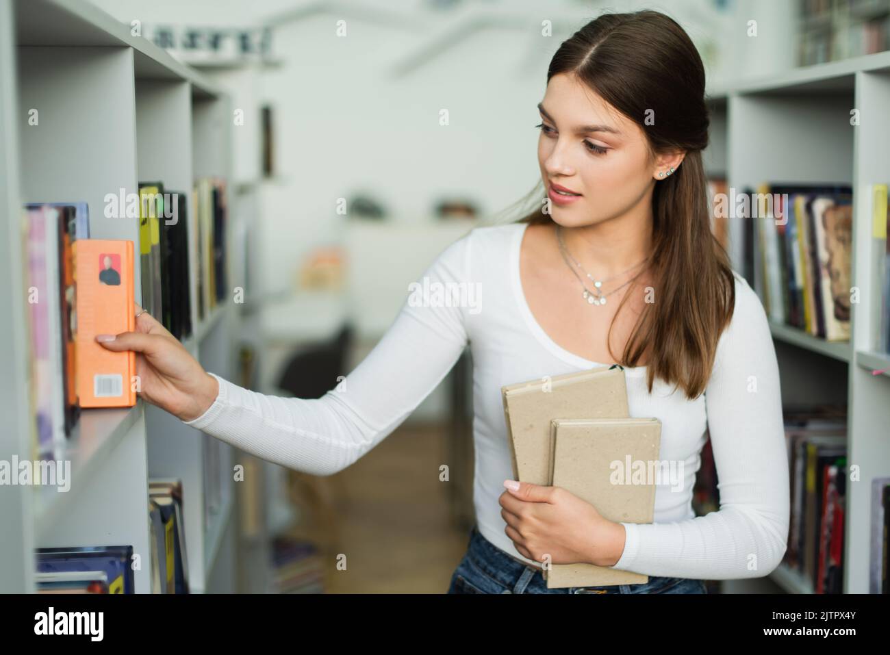 brunette teenage girl choosing books in library,stock image Stock Photo ...
