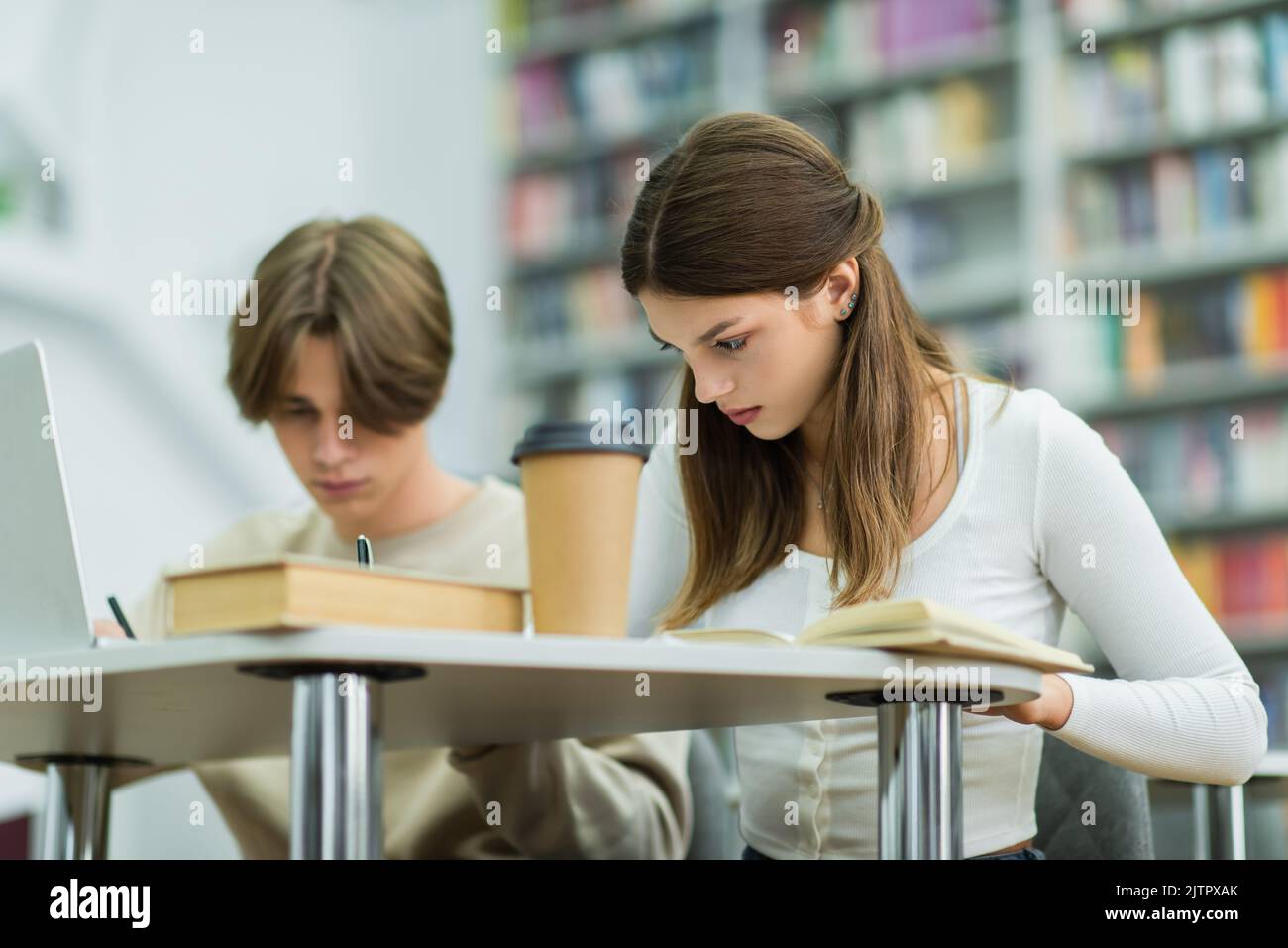couple of teenage students writing near laptop while studying in ...
