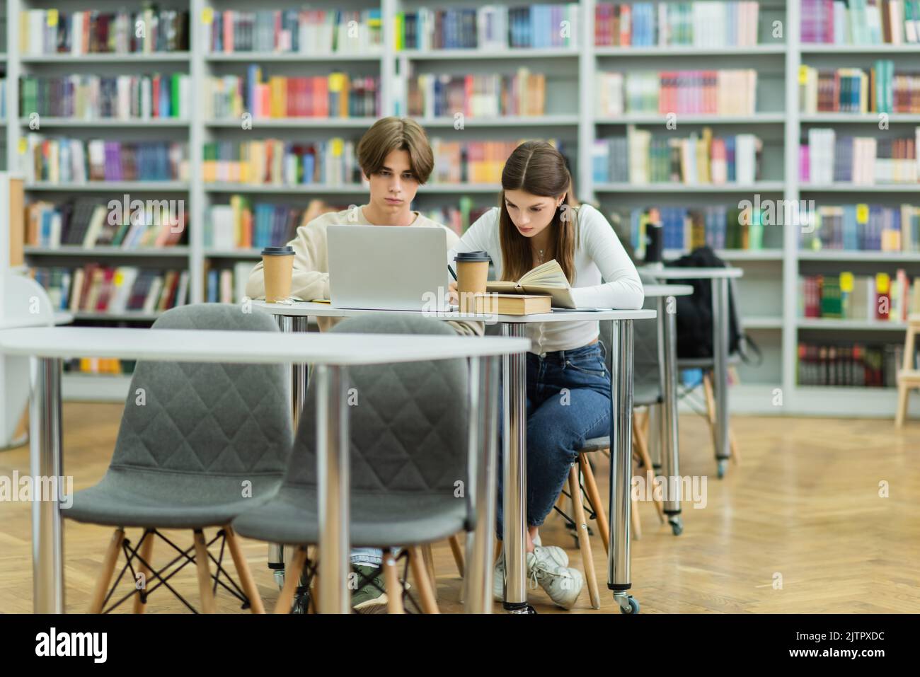 teenage students studying near laptop and books in library,stock image ...