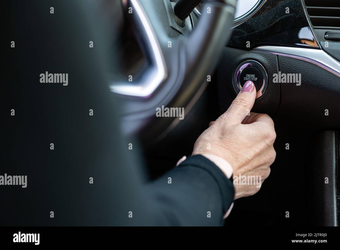 Woman starts the car engine with start-stop button. Modern car interior ...