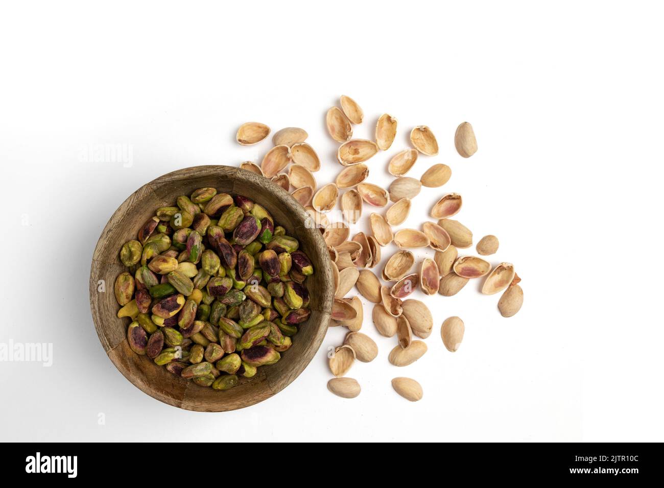 wooden bowl of peeled pistachio with shell scattered around isolated on ...