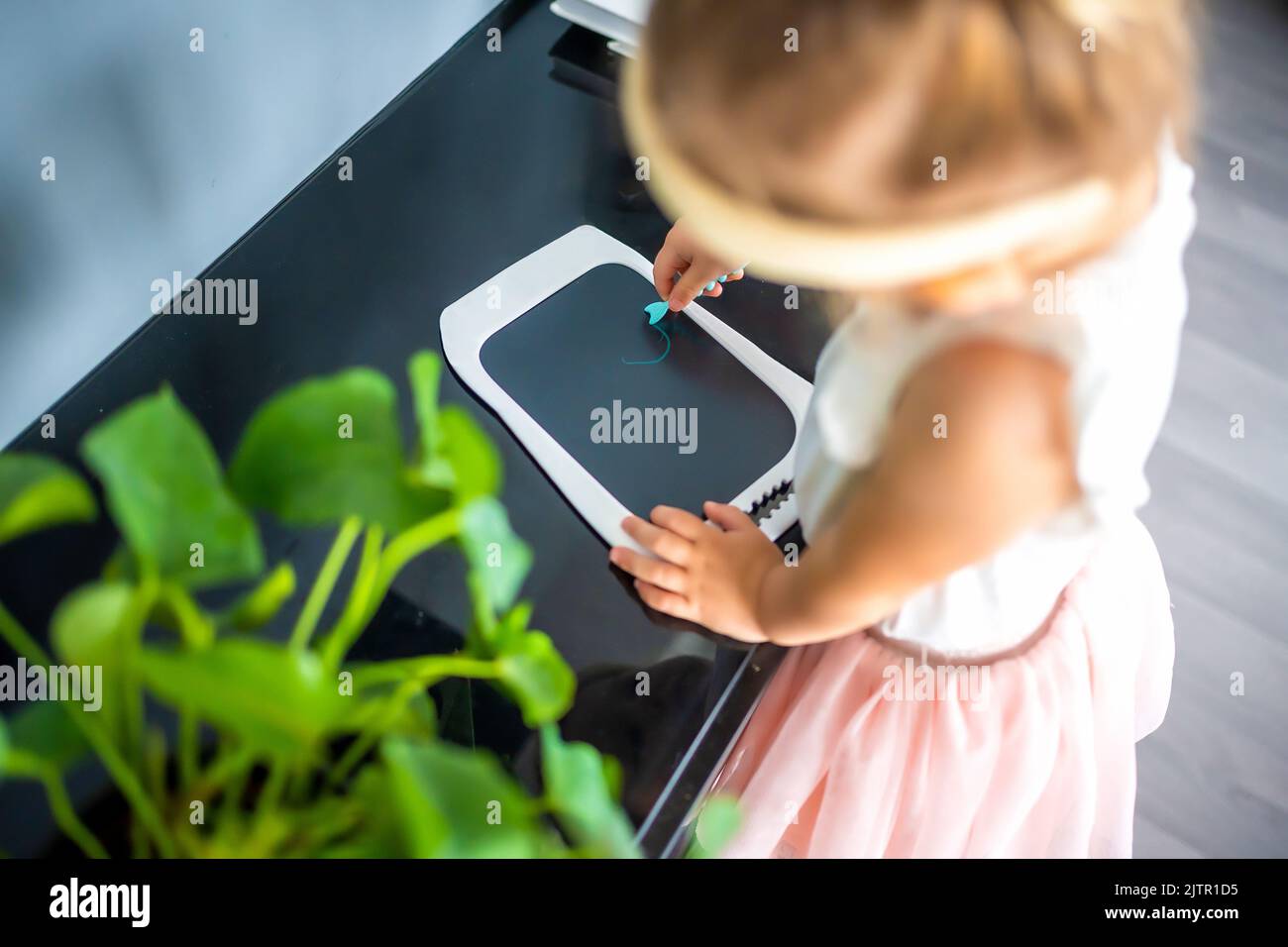 Little girl is drawing on Led tablet at home. View of child hand with ...