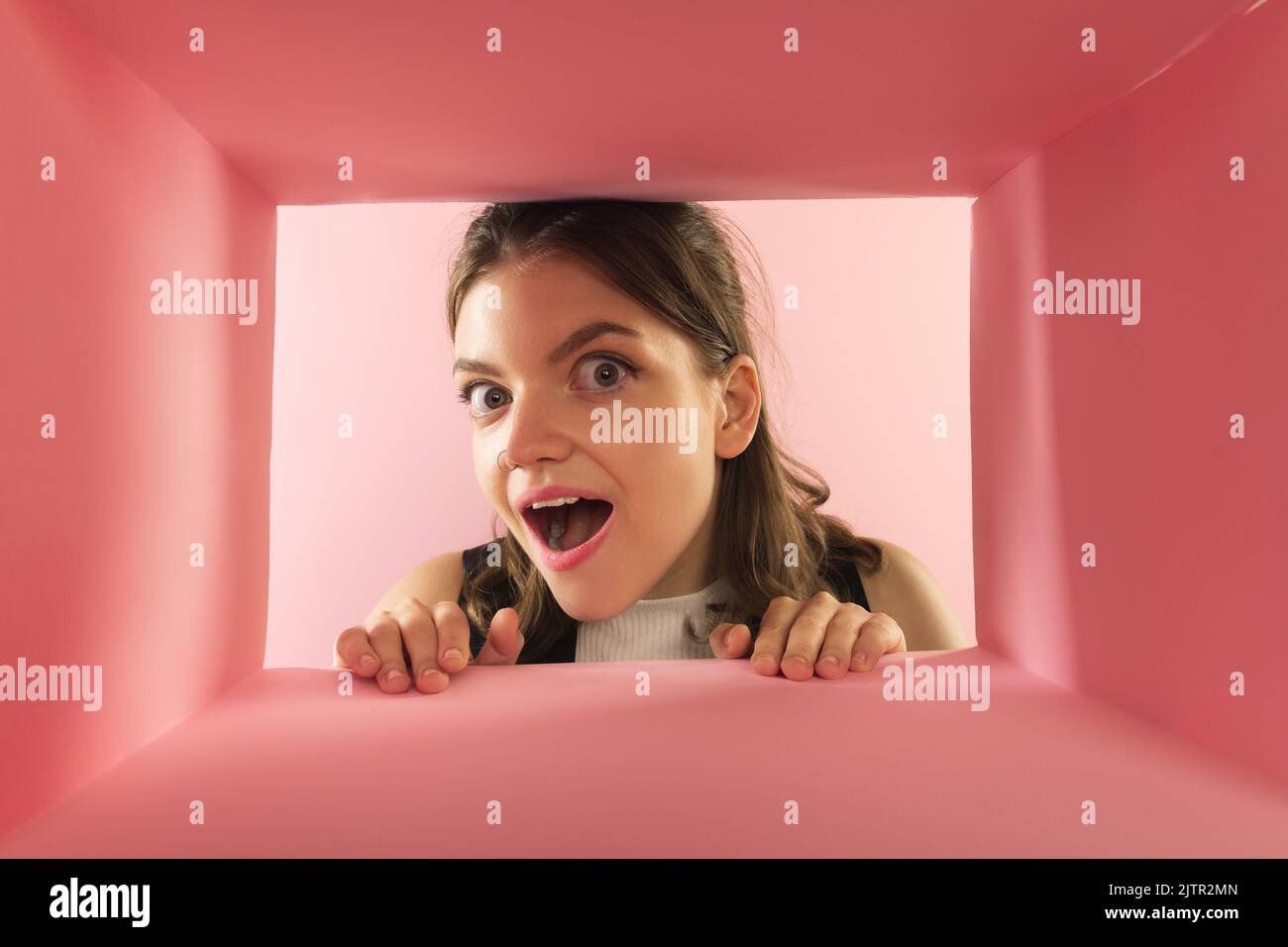 Happy and excited young girl looking inside carton box. Looking ...