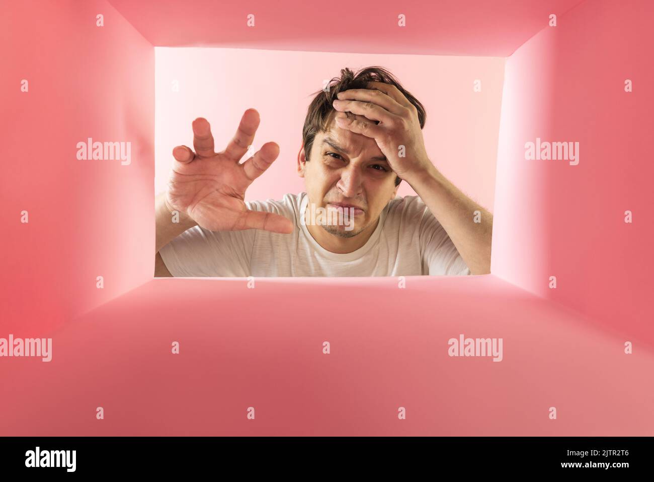 Young man looking inside box with unpleasant face. Emotions of ...