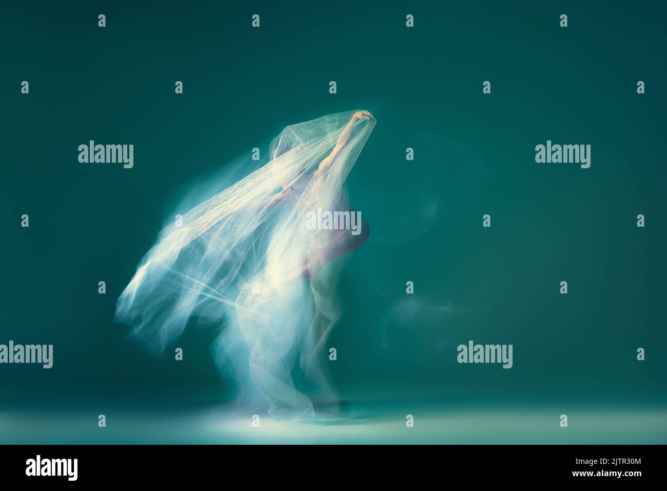 Ghostly vision. Tender girl, ballet dancer dancing with white cloth ...