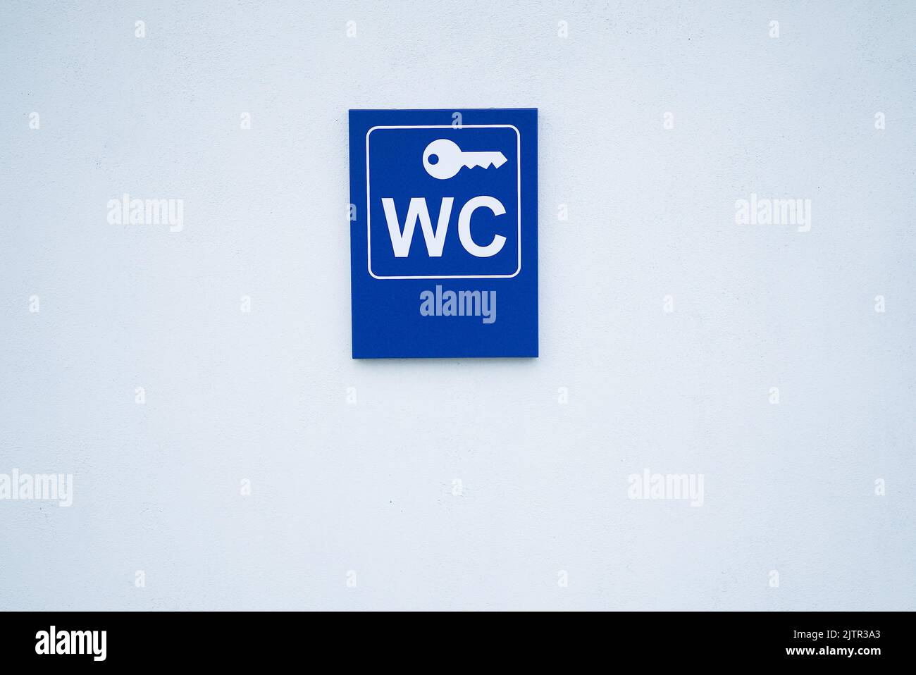 WC sign on the wall with key sign above it Stock Photo - Alamy