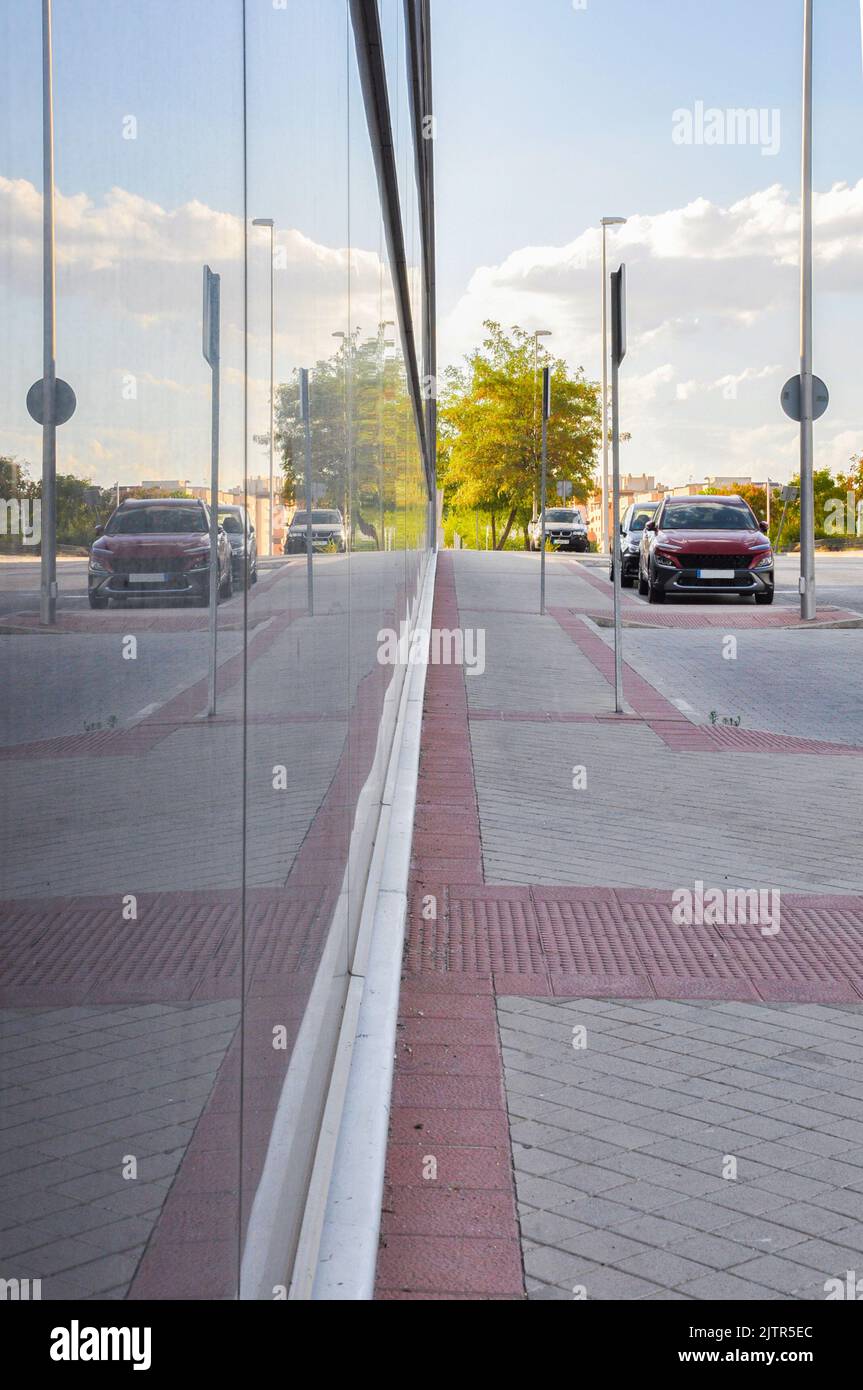 Street with cars reflected on a glass building Stock Photo - Alamy