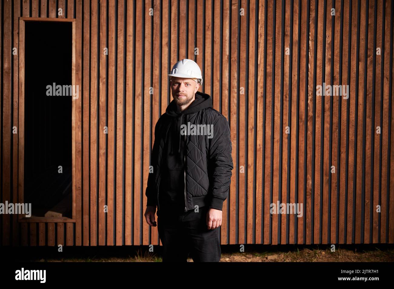 Portrait of male builder building wooden frame house. Man standing on ...