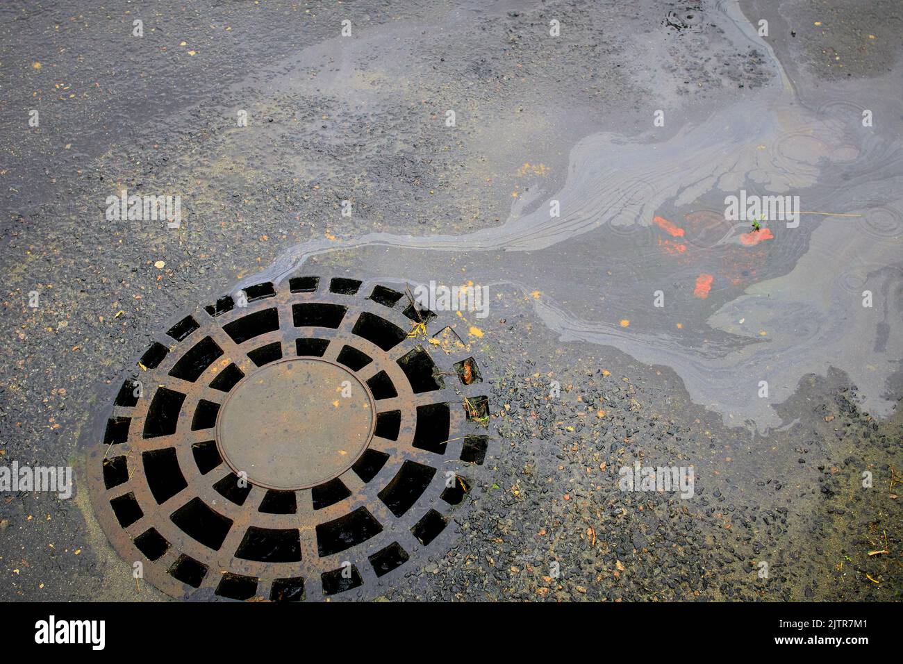 Oil spills of gasoline against the background of an asphalt road flow ...