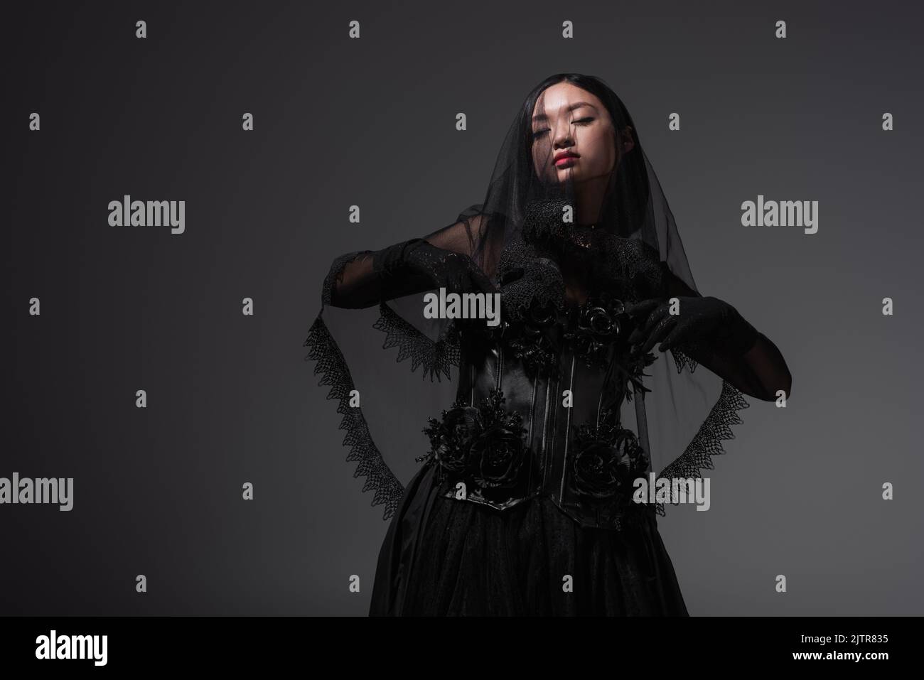 young asian woman in gothic outfit with black veil posing isolated on ...