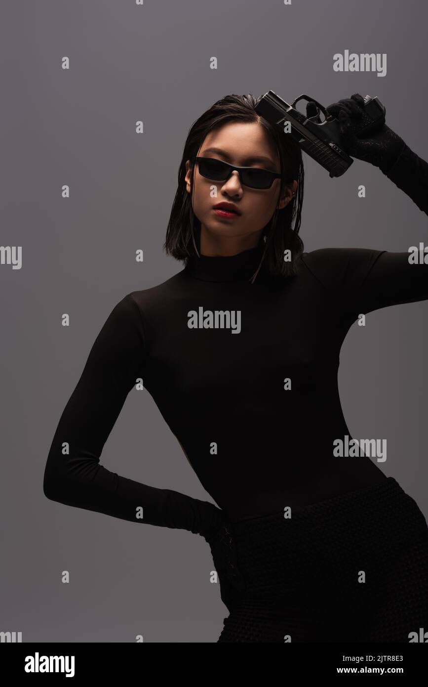 dangerous asian woman in black outfit and stylish sunglasses holding ...