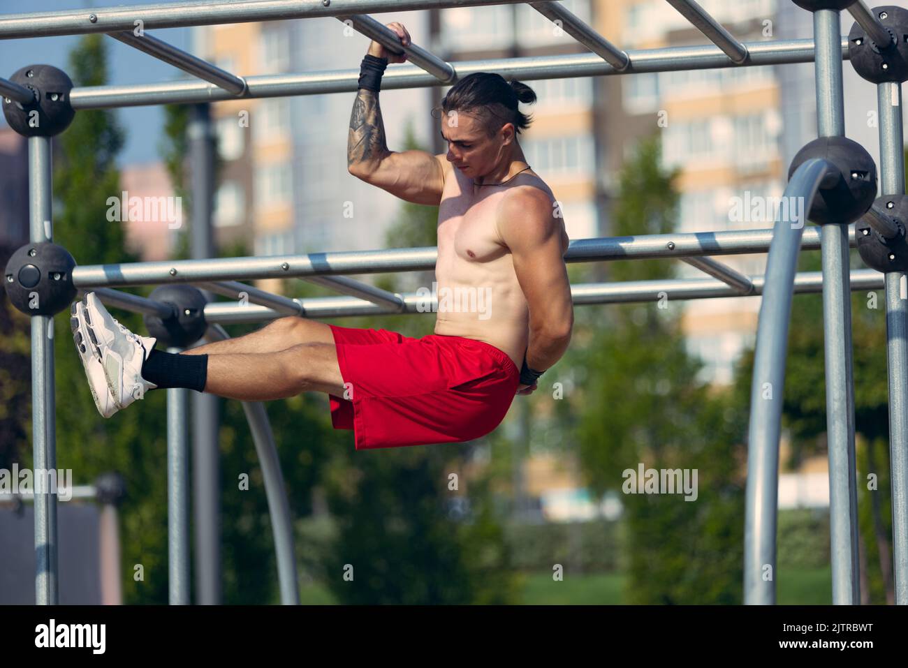 Young strong muscular man doing strength exercises on workout ground at ...