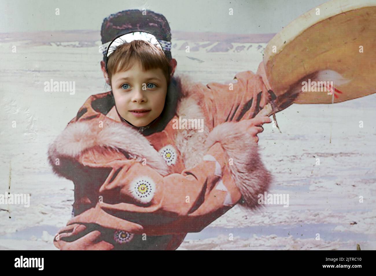 Happy child takes place of shaman with tambourine using photo stand-in ...
