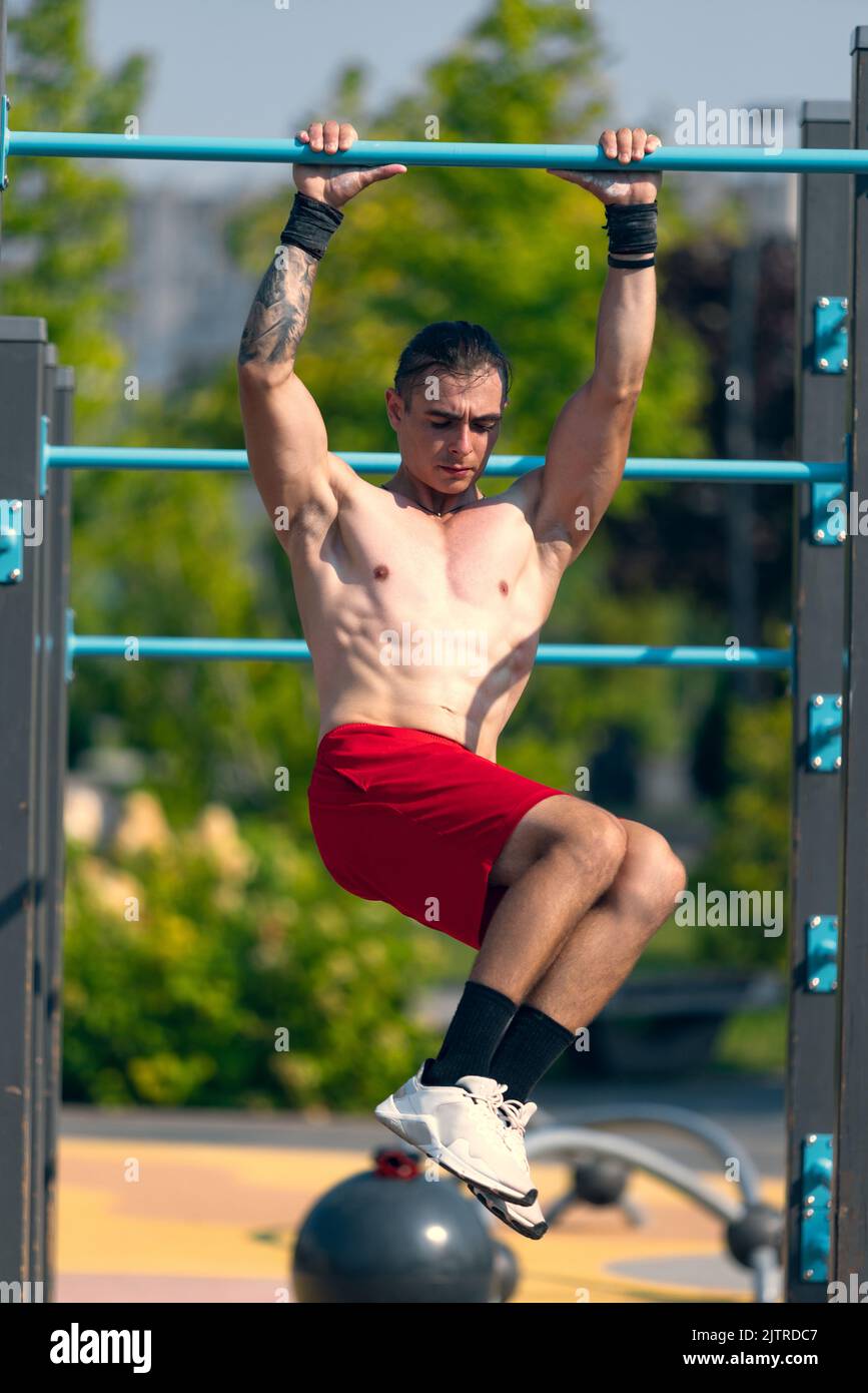 Young strong muscular man doing strength exercises on workout ground at ...