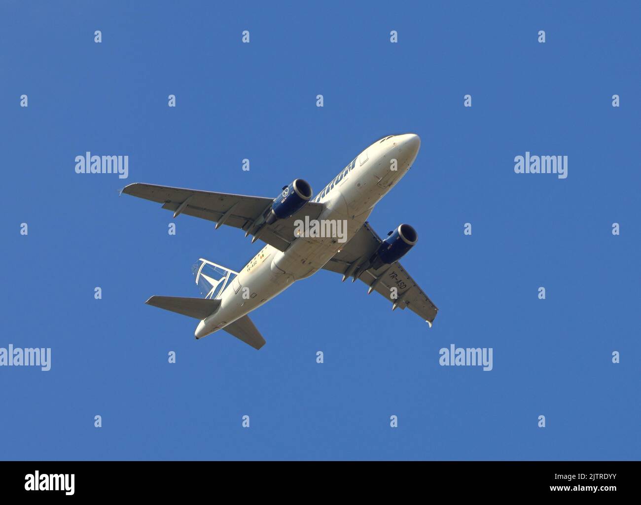 Passenger Jet Aeroplane flying directly above in a bright blue sky ...
