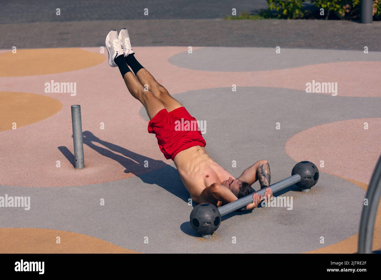 Young strong muscular man doing strength exercises on workout ground at ...