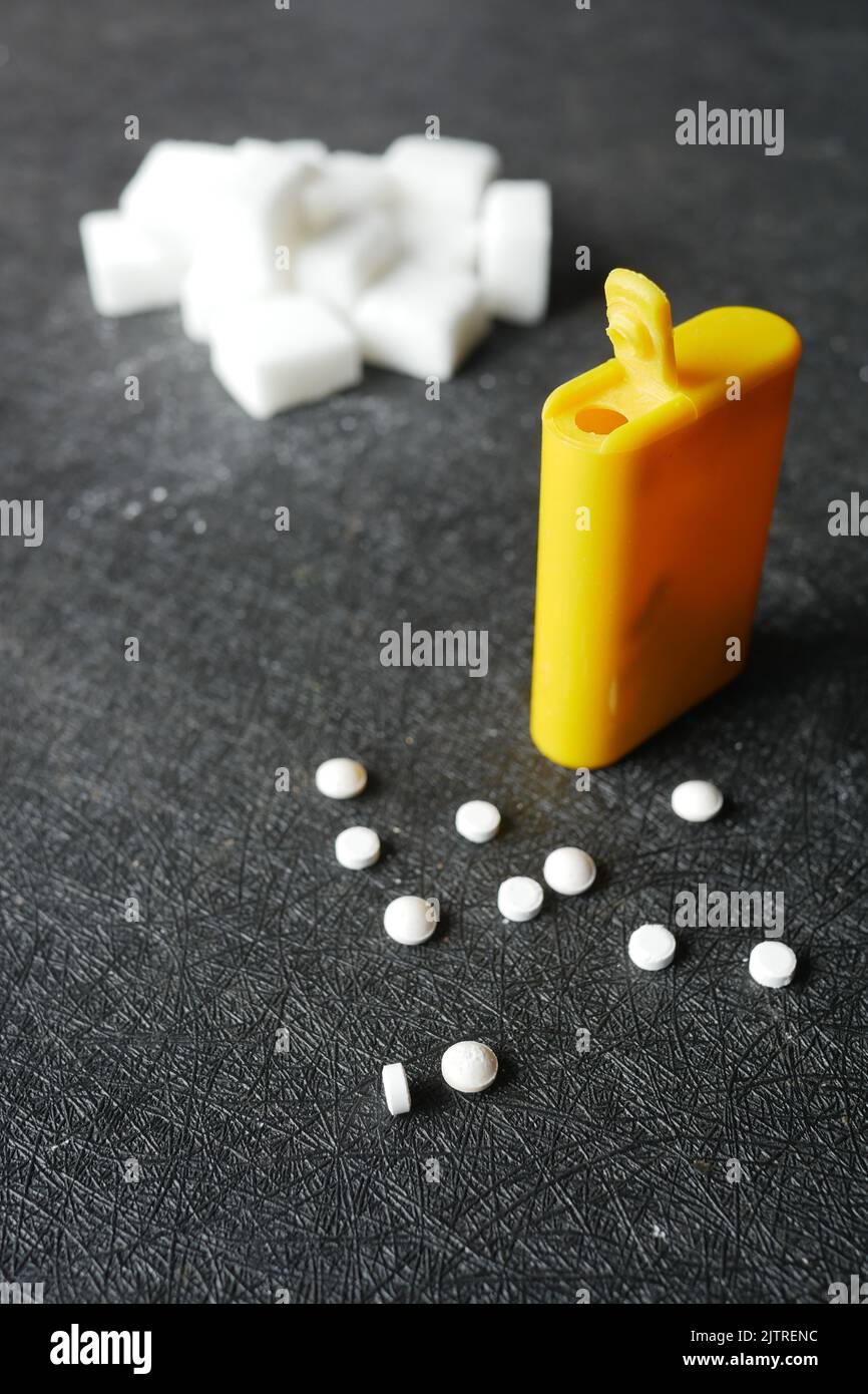 comparing artificial sweetener and sugar cube container on black Stock ...