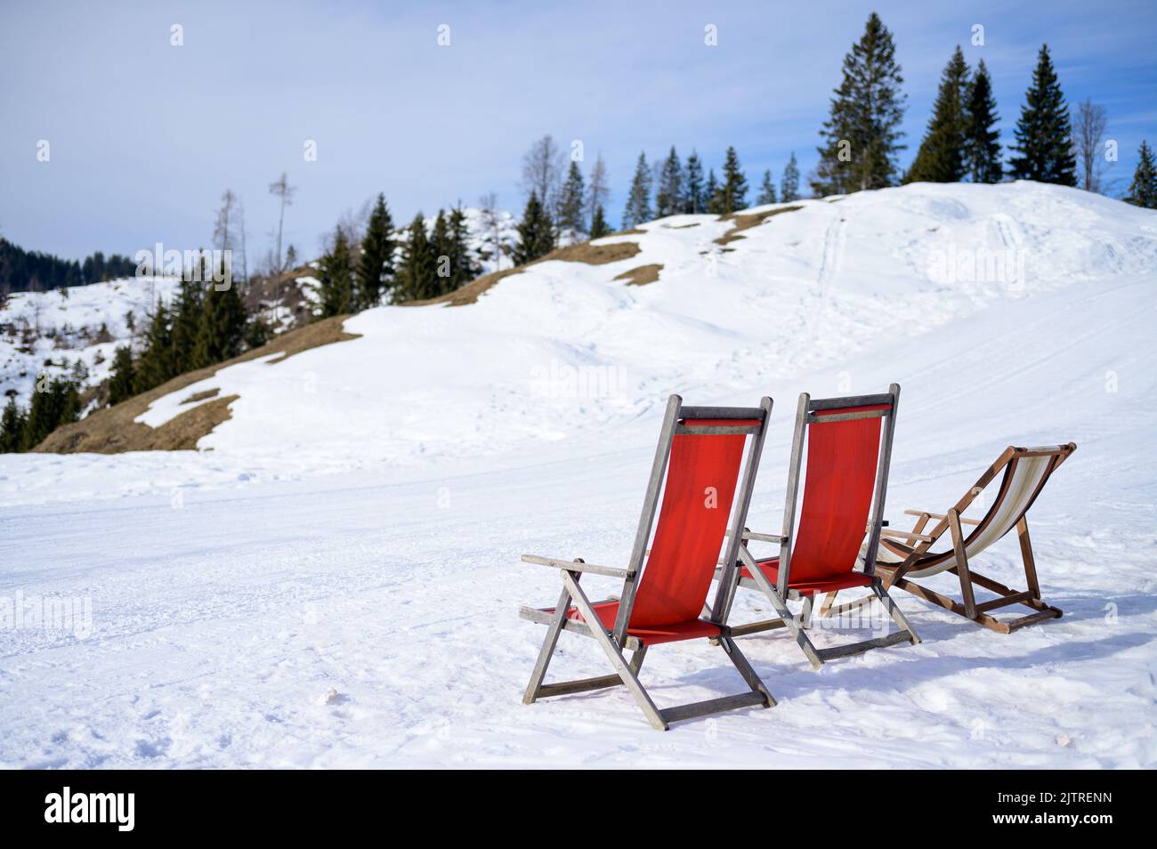 Two red chairs standing in the snow on a mountain, sunny day in winter ...