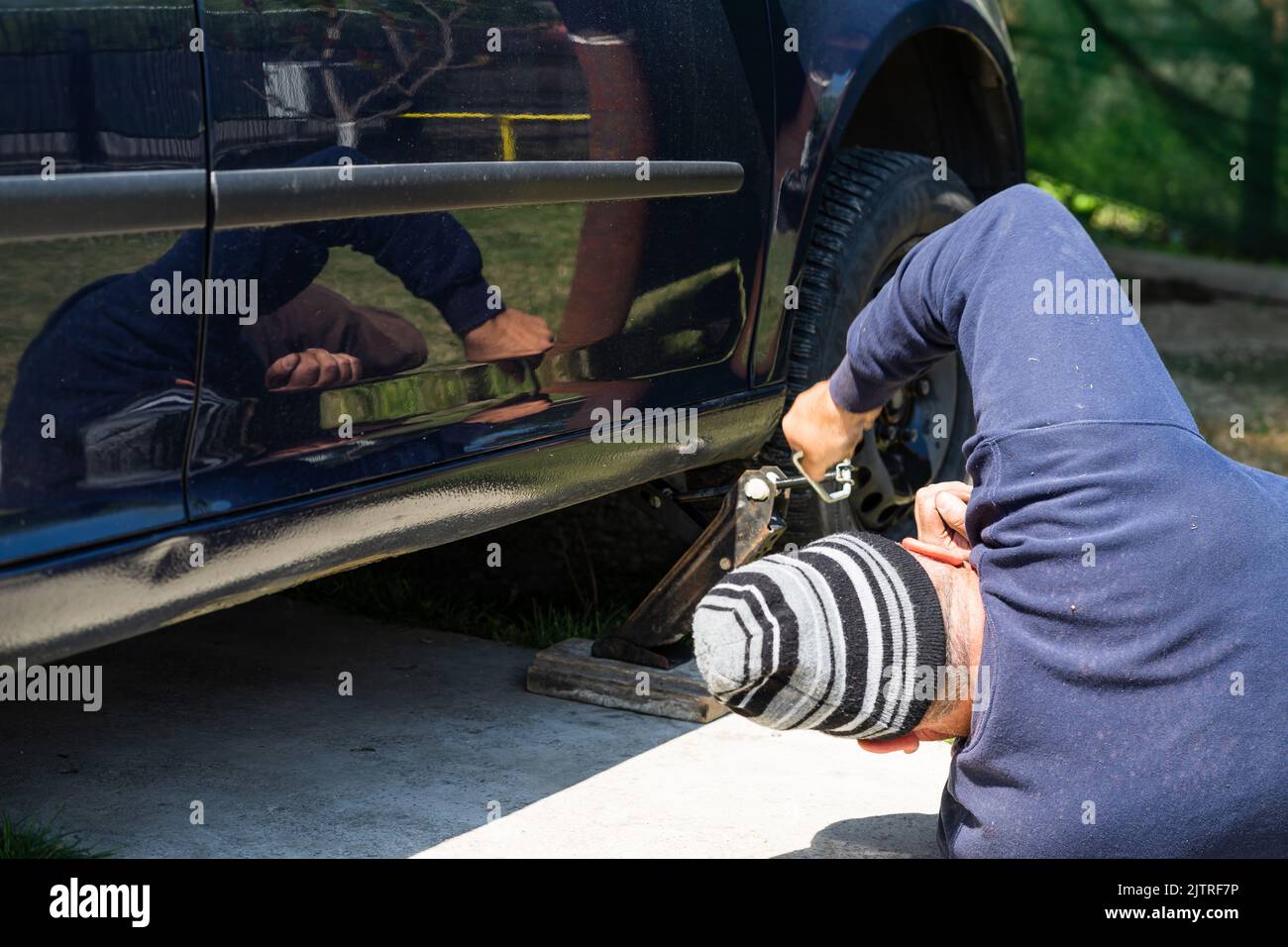 Mechanic changing wheel on car with manual wrench. Mechanic replacing ...