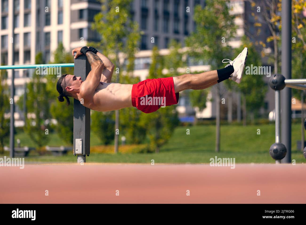 Young strong muscular man doing strength exercises on workout ground at ...