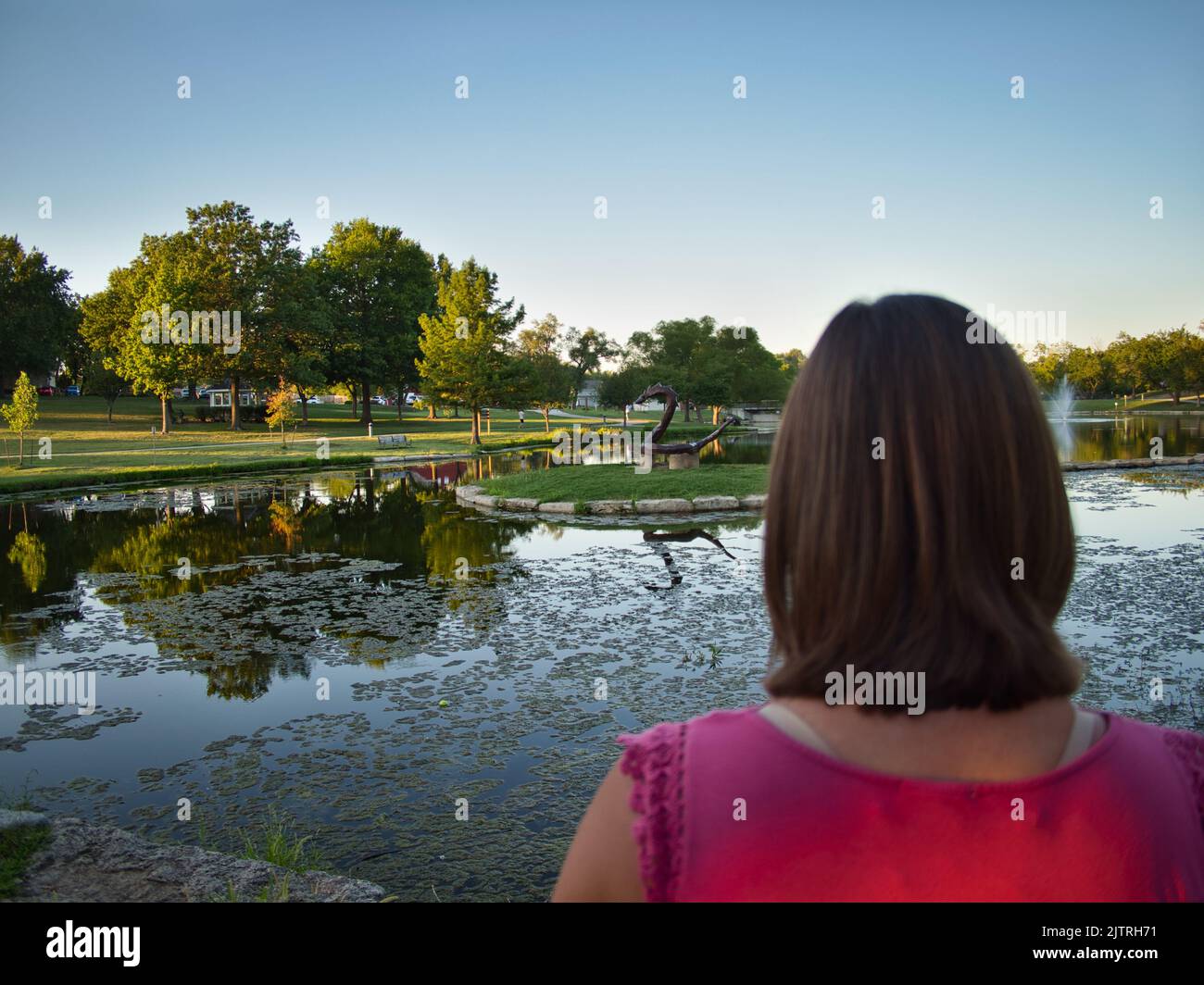 Brunette standing by the reflective waters of Sar Ko Par Park in Lenexa ...