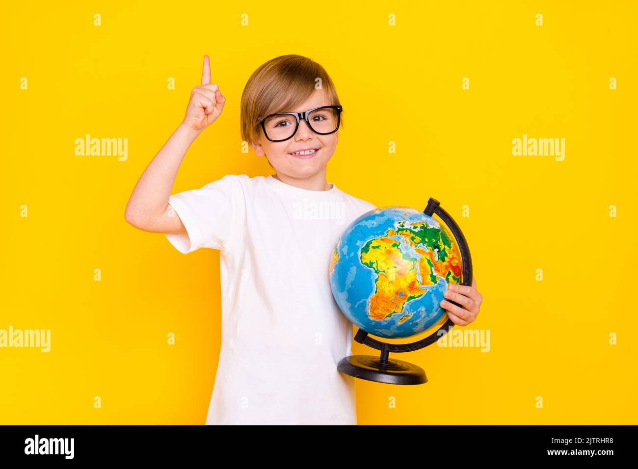 Portrait of handsome cheerful brainy pre-teen boy holding globe point ...