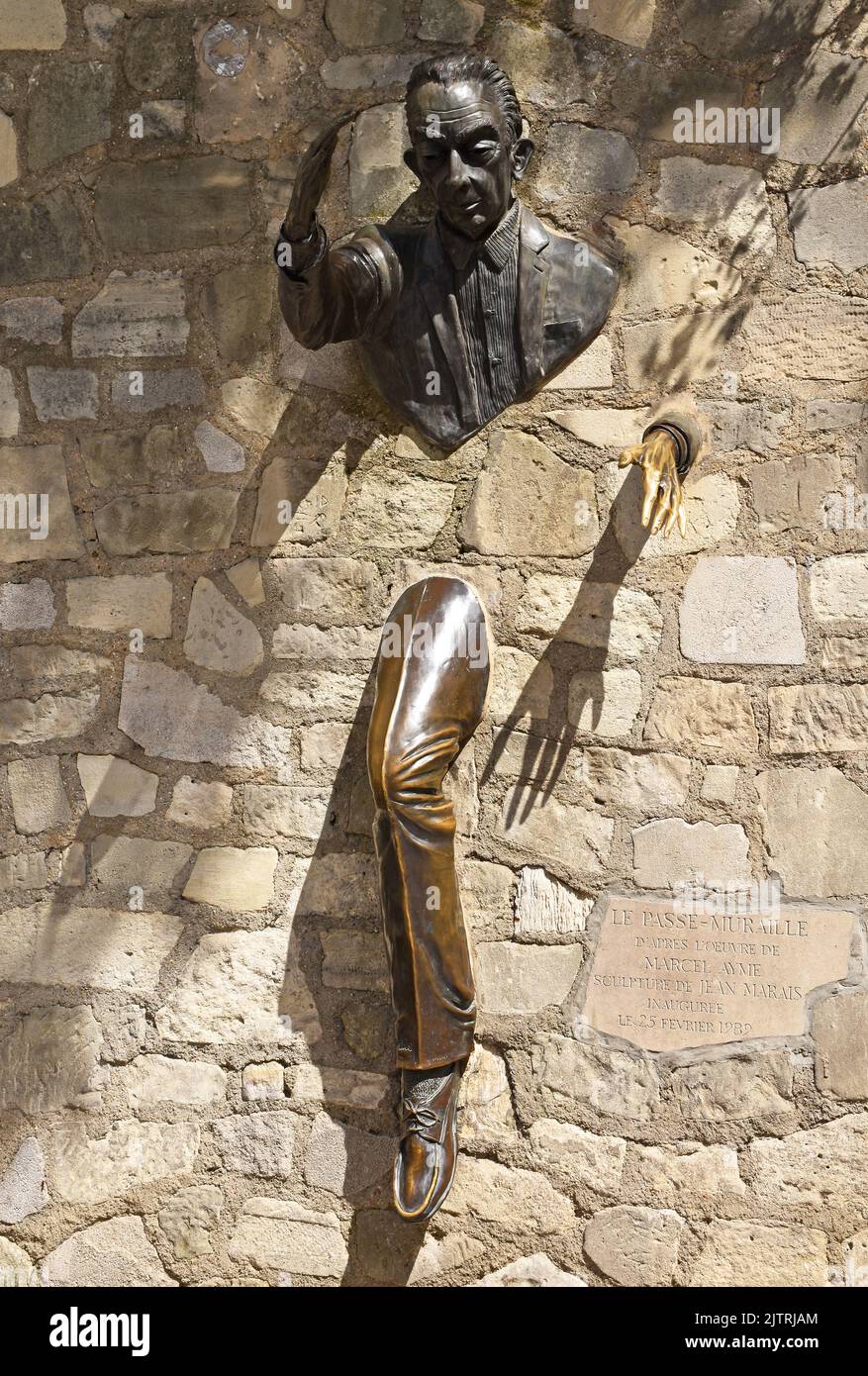 Bronze sculpture of a man apparently walking through a stone wall, an ...