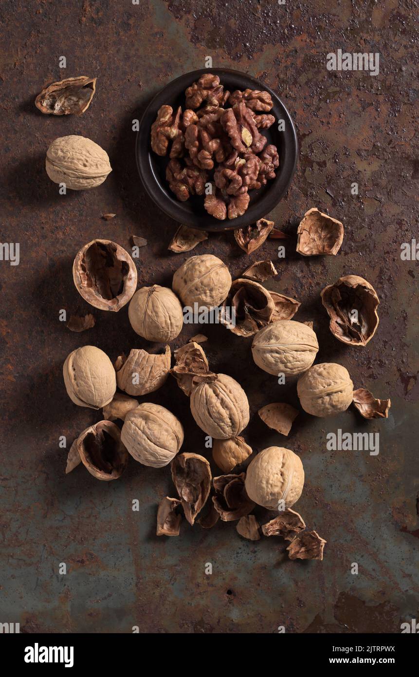 Whole, peeled and broken walnuts on a rusty iron background, top view ...