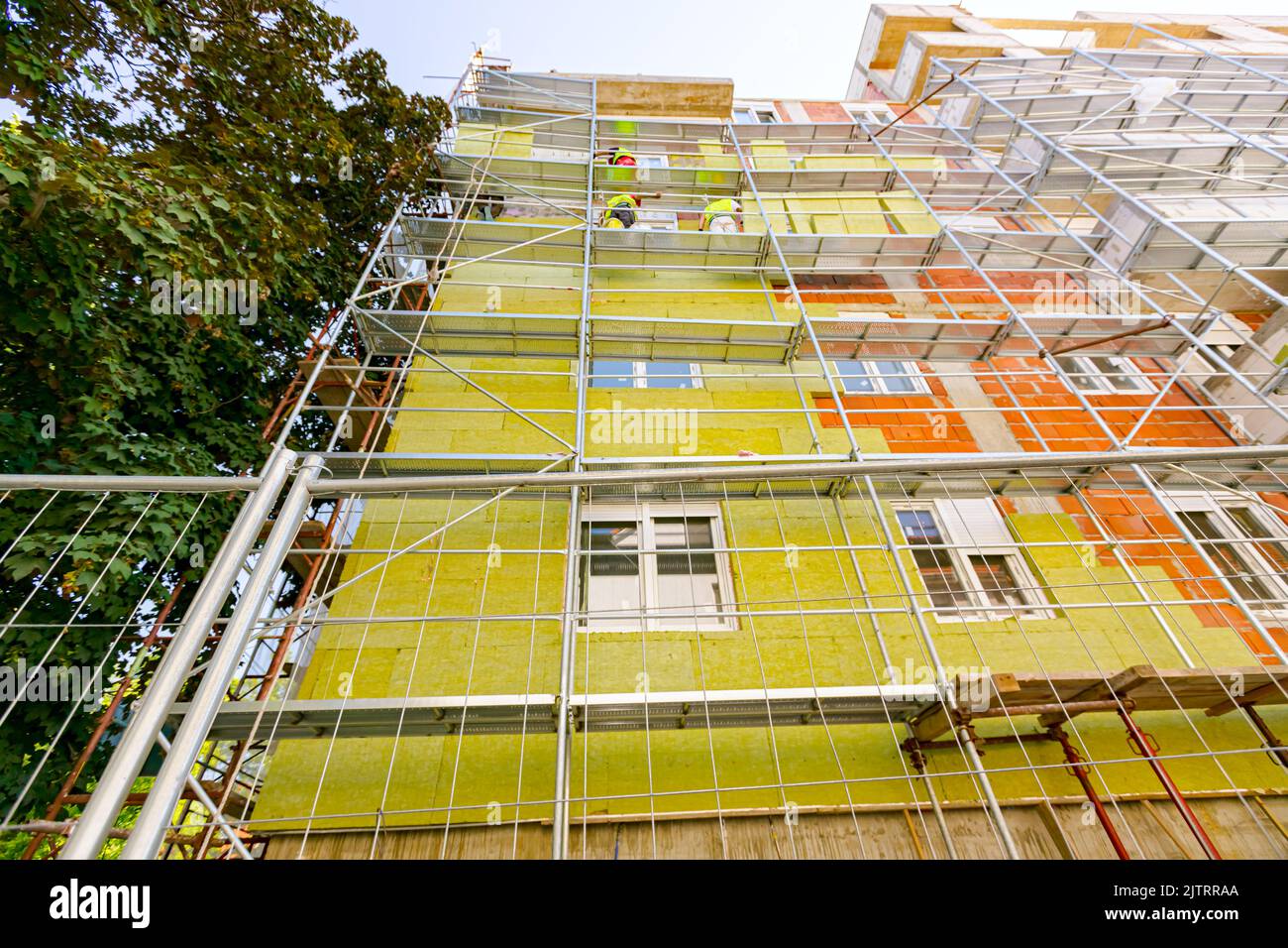View from below on fenced thermally insulated building. Riggers on ...