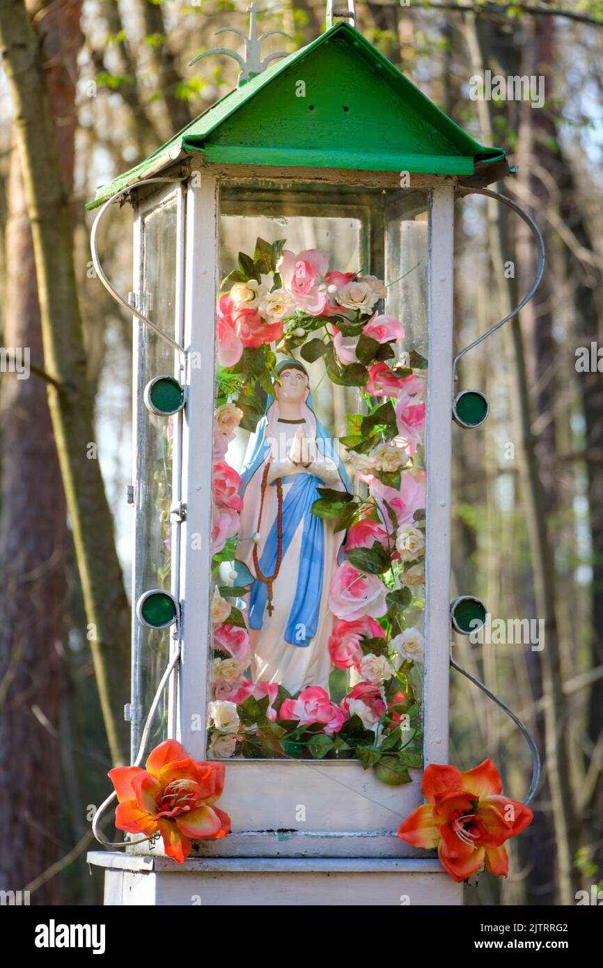 A roadside chapel in the forest, a Maria with a rosary and flowers ...