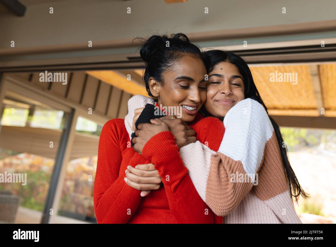Happy biracial teenage daughter with eyes closed hugging mother from behind at home Stock Photo ...