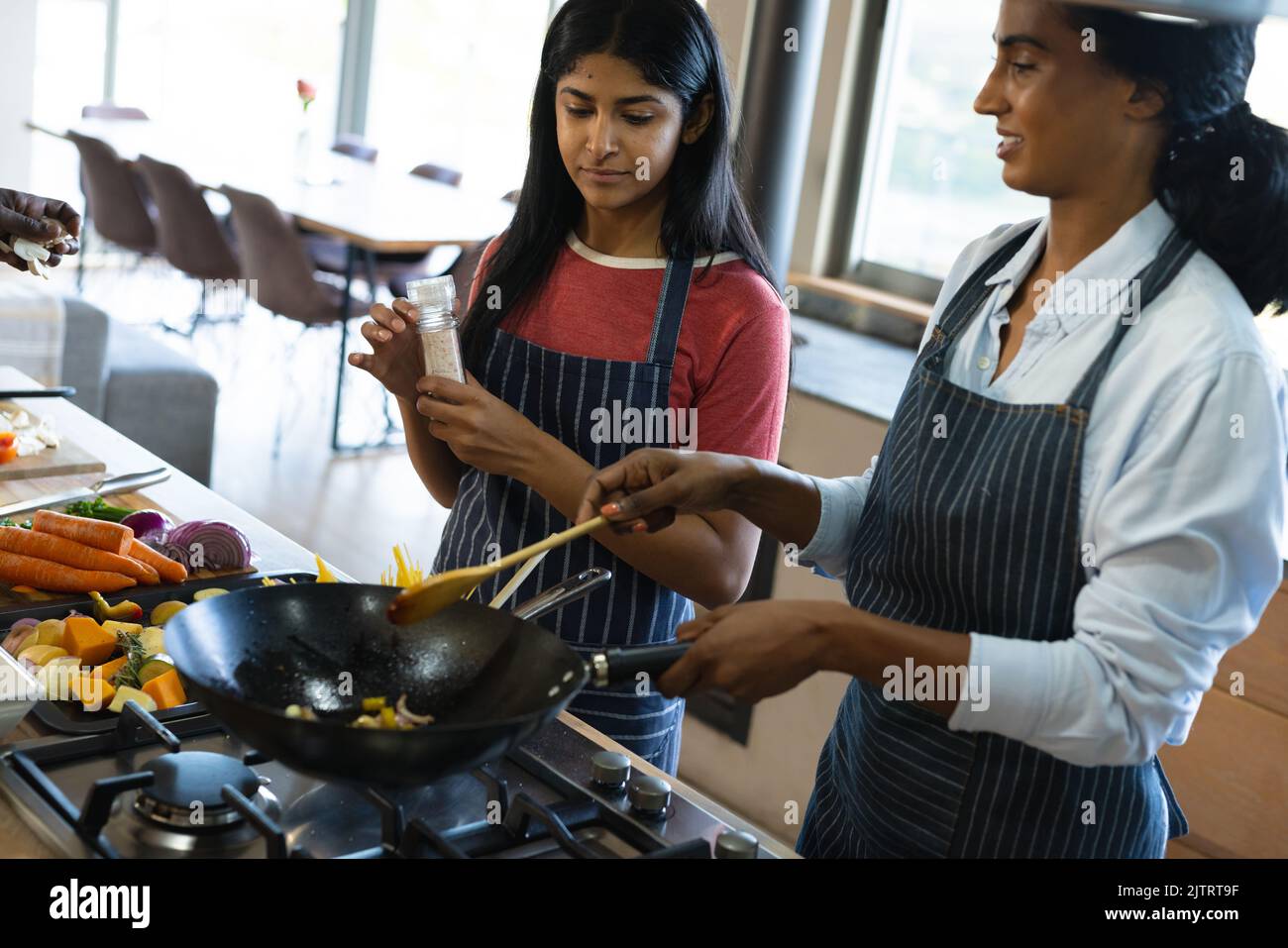Biracial teenage girl looking at mother cooking food on stove in ...