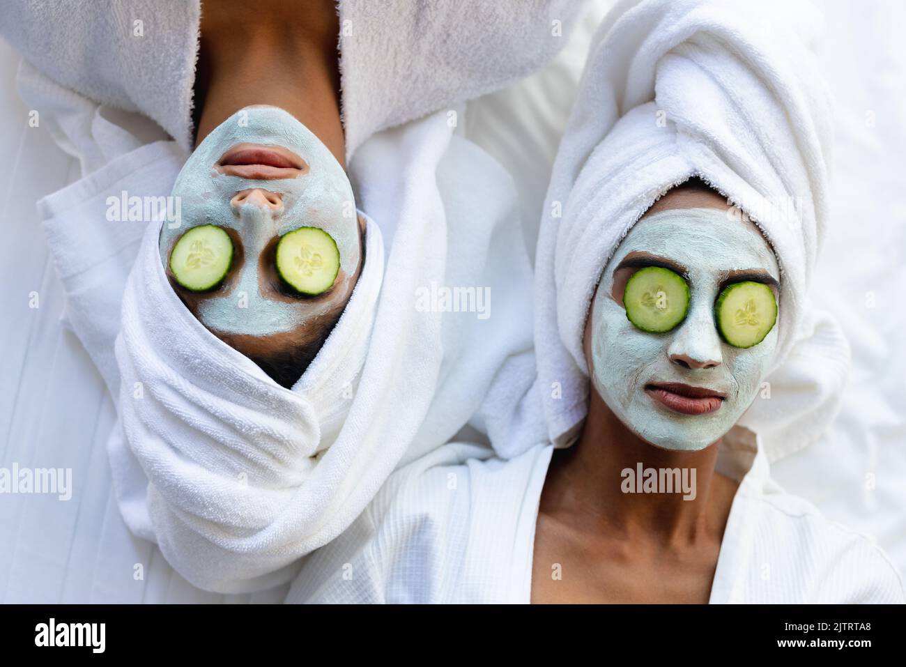 Biracial mother and daughter with facial masks and cucumber slices on ...