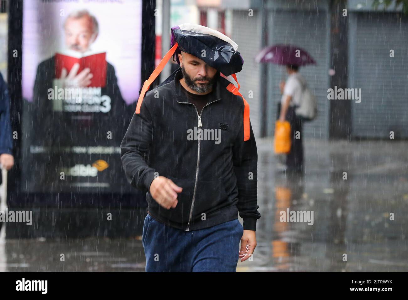 A man shelters under a bag during rainfall in London Stock Photo - Alamy